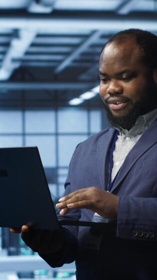 Vertical Programmer In Data Center Typing On Laptop Running Error