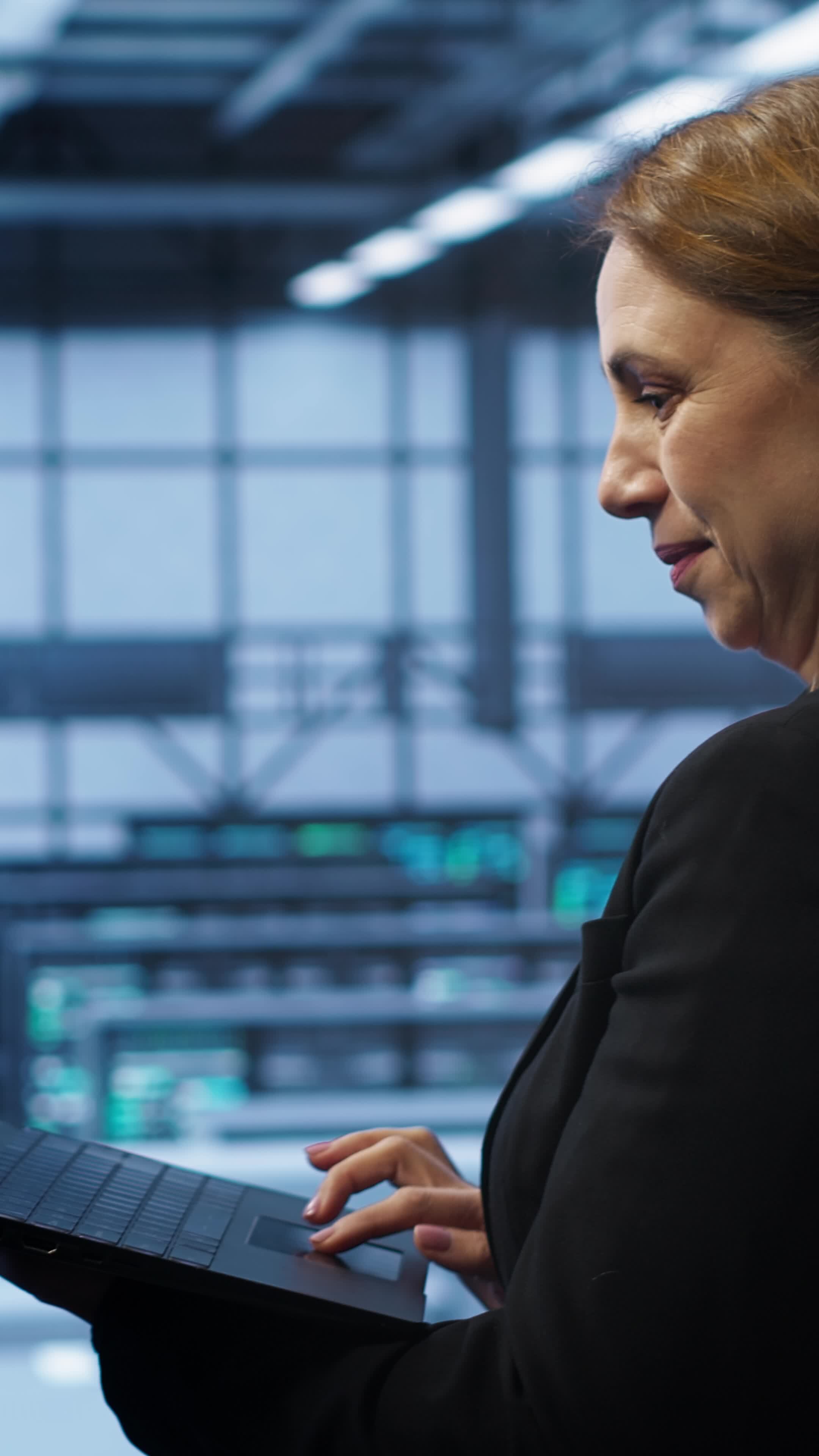 Vertical Computer scientist doing yearly maintenance using laptop to prolong data center ...