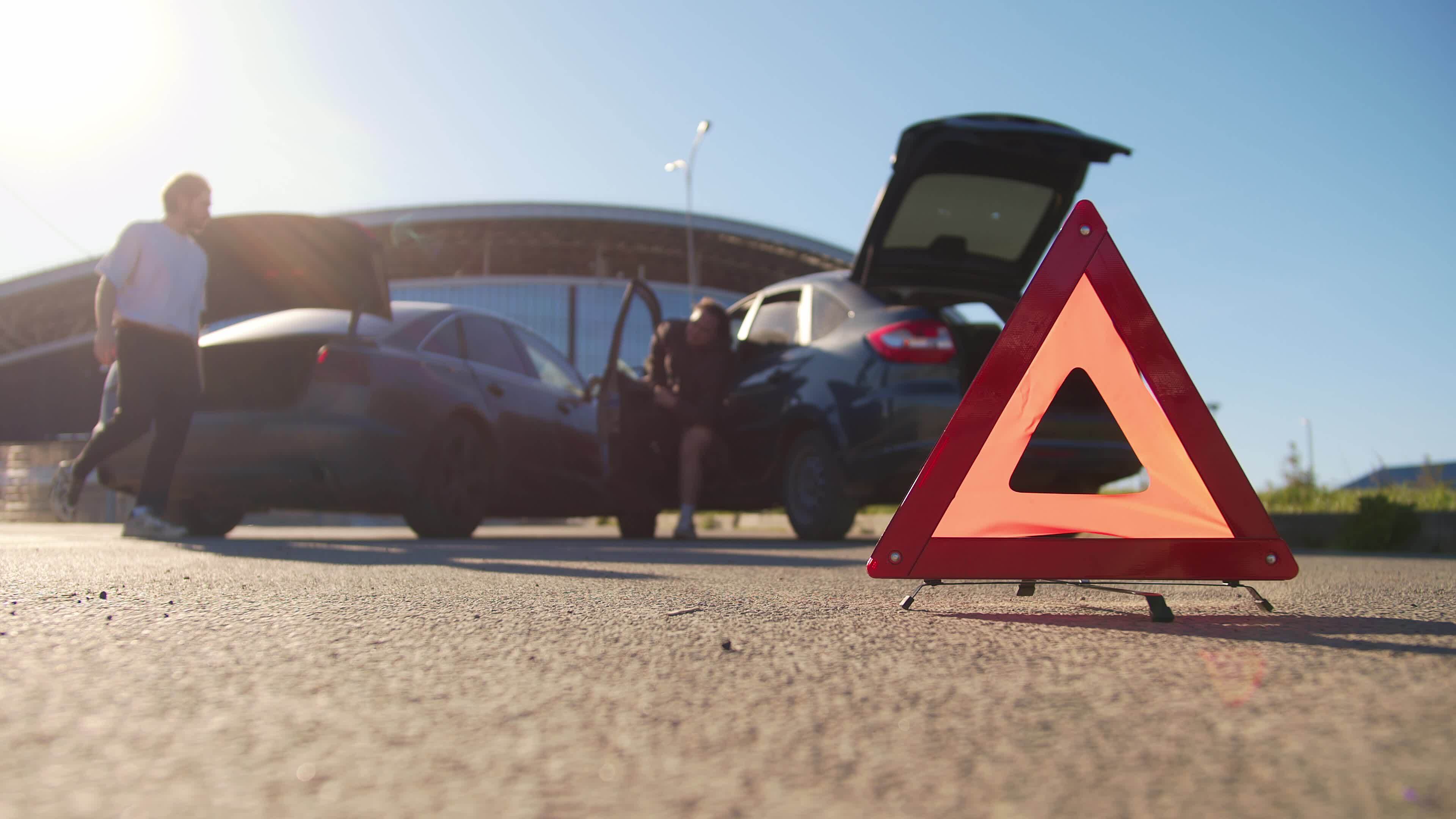 Men involved in the car accident set up a warning triangle in accordance with driving ...
