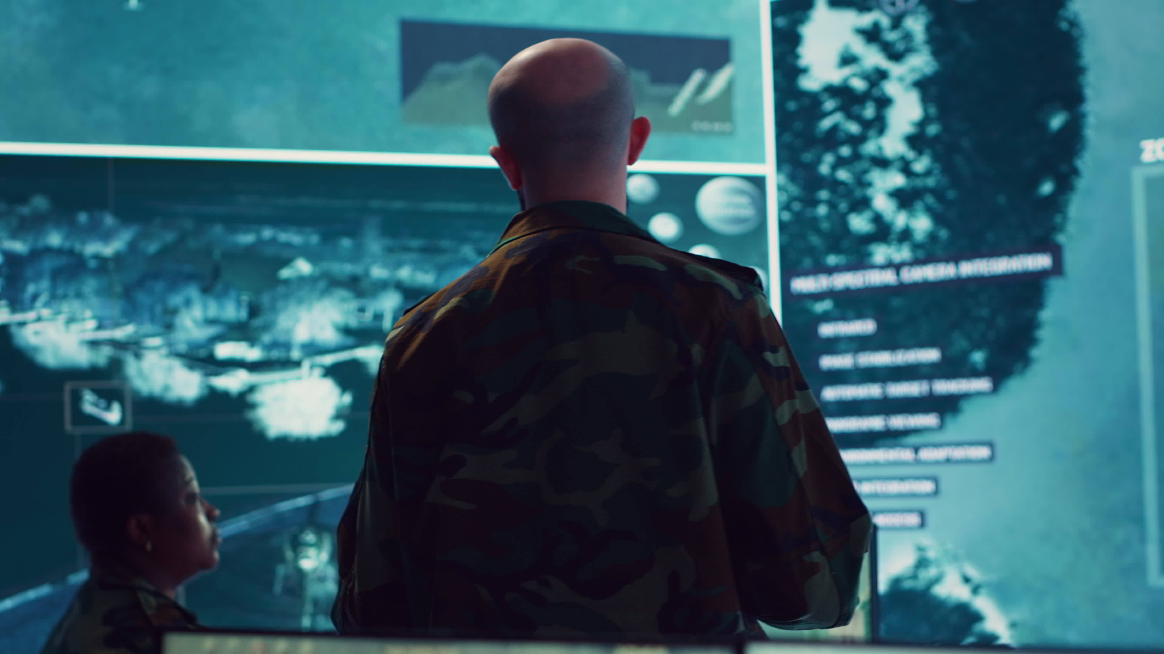 Army Officer Examining Real Time Satellite Data On Big Screen In