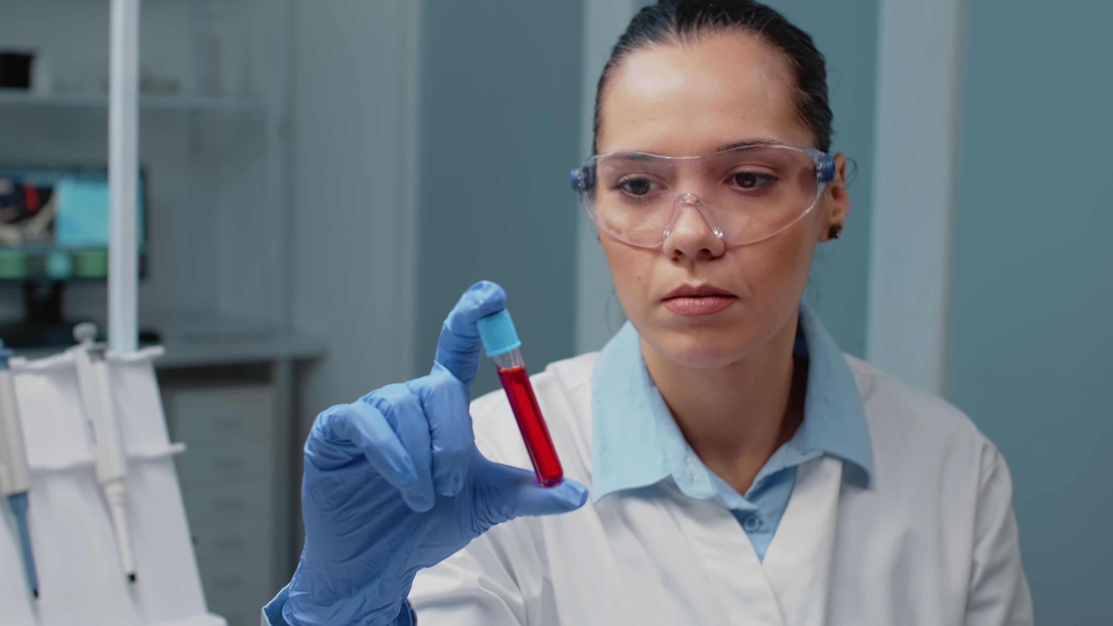 Portrait of chemist holding glass vacutainer with blood in laboratory ...