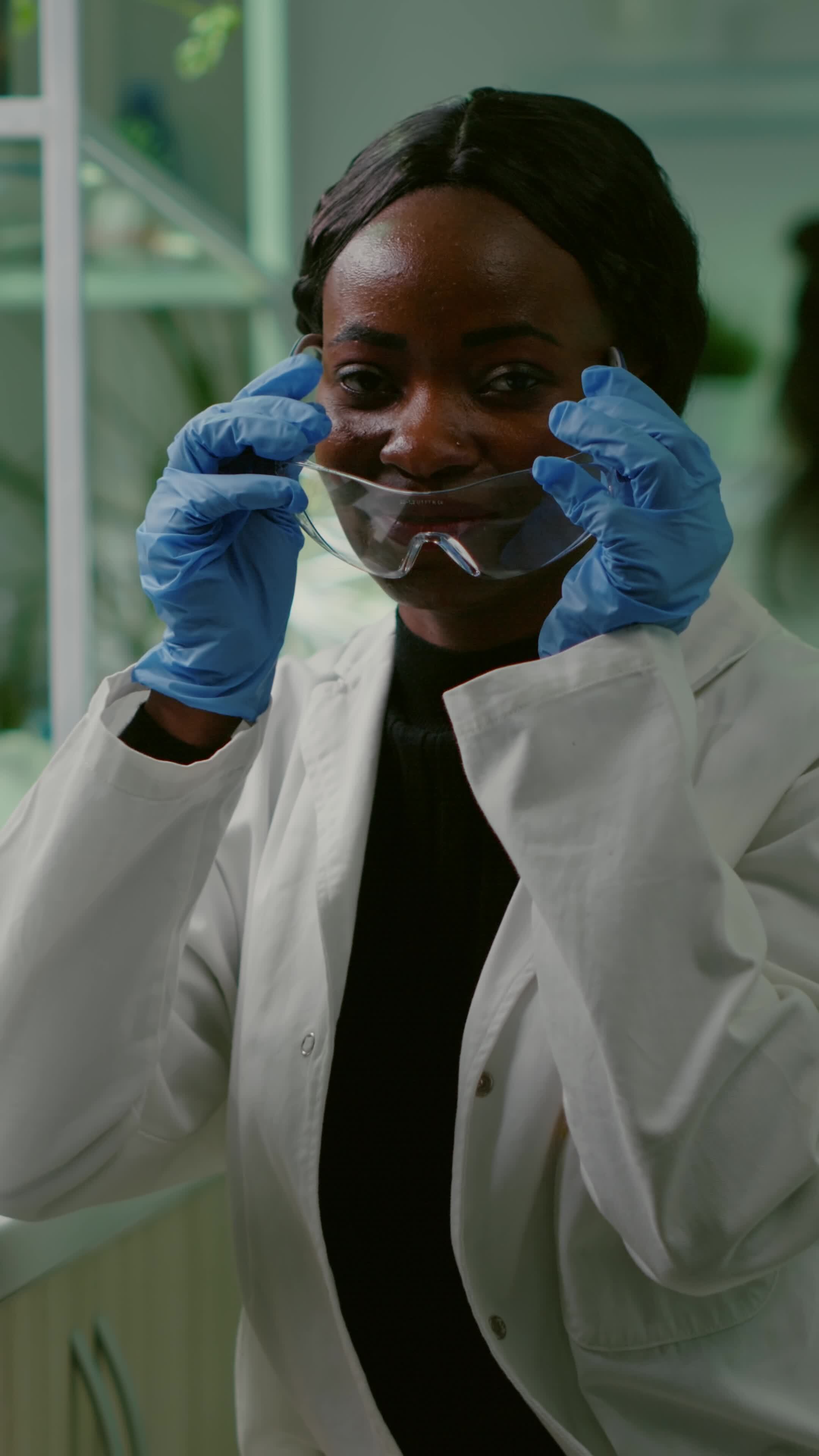 Vertical . Portrait of african biologist in white coat looking into ... Vertical . Portrait of african biologist in white coat looking into ...