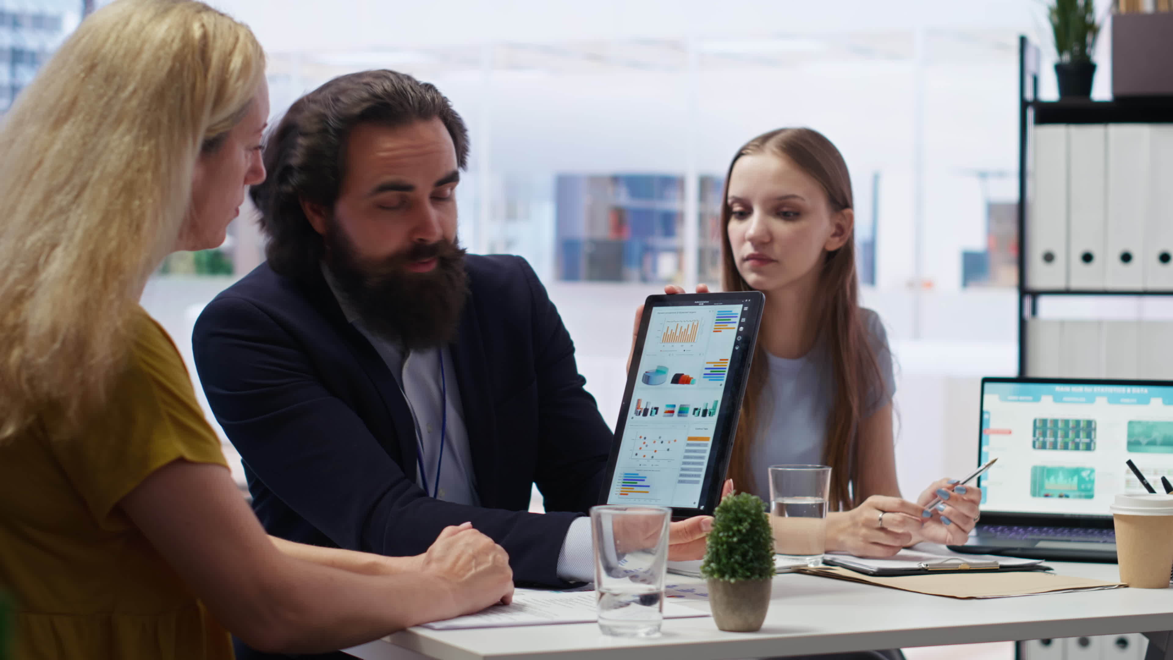 Financial Advisor Showing Statistical Graphs On Tablet To Clients