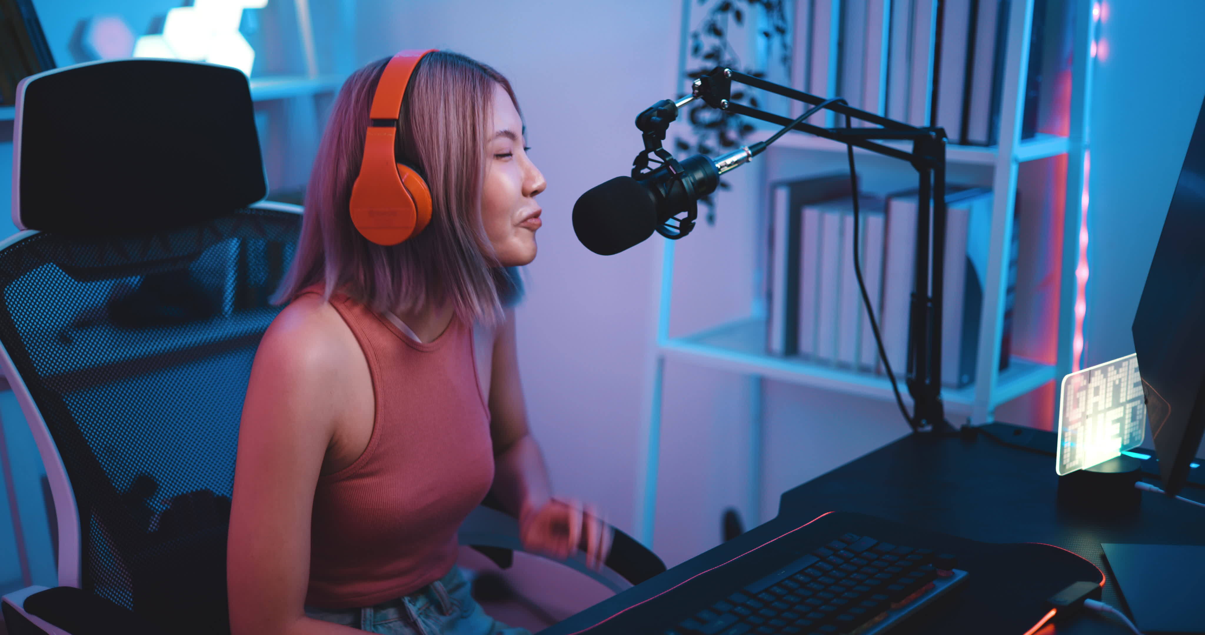 Footage of Young Asian woman influencer wearing headphones talking into a microphone while ...