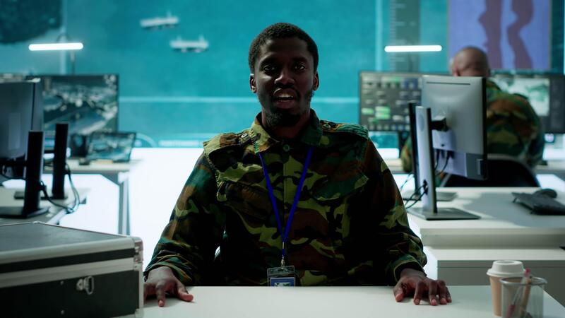 Army personnel in a high tech command center attends a videocall ...