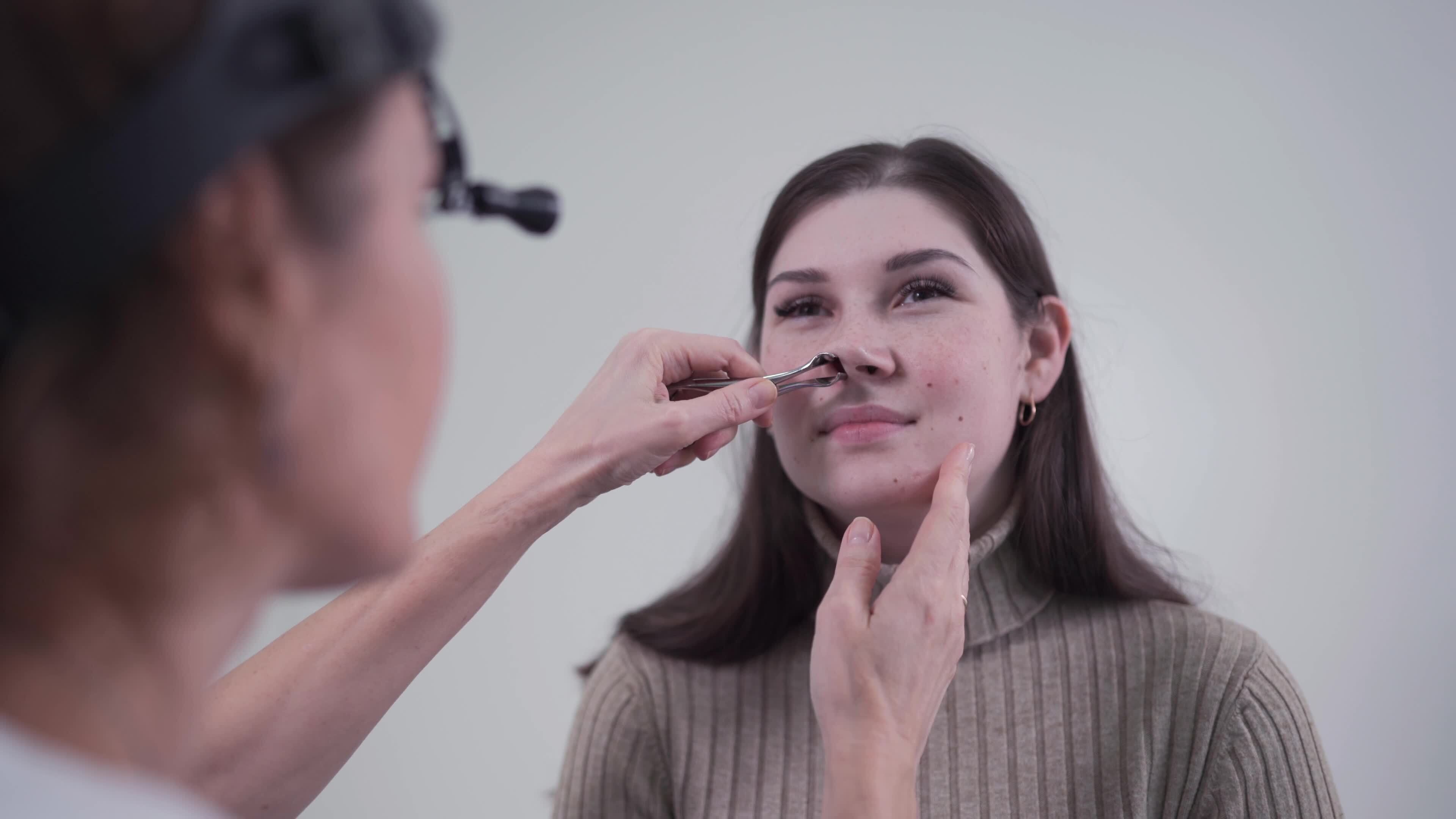 Female Ent Doctor Examines Patients Sinuses With Medical Instrument In Modern Clinic