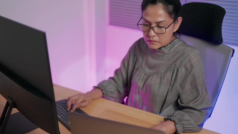 Freelance Web Designer Sitting At Desk In Evening Working Wondering