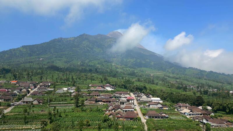 Aerial of active Merapi volcano and picturesque village on its slope ...