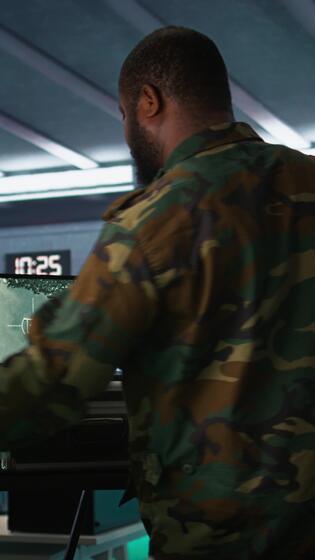 Vertical Air force officer performing tactical level surveillance in command room using laptop ...