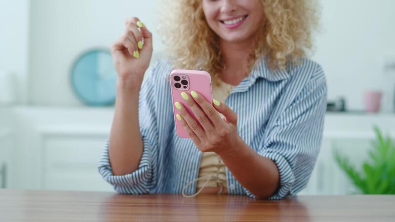 Selective focus on a modern smartphone in the hands of a pretty woman scrolling news feed ...