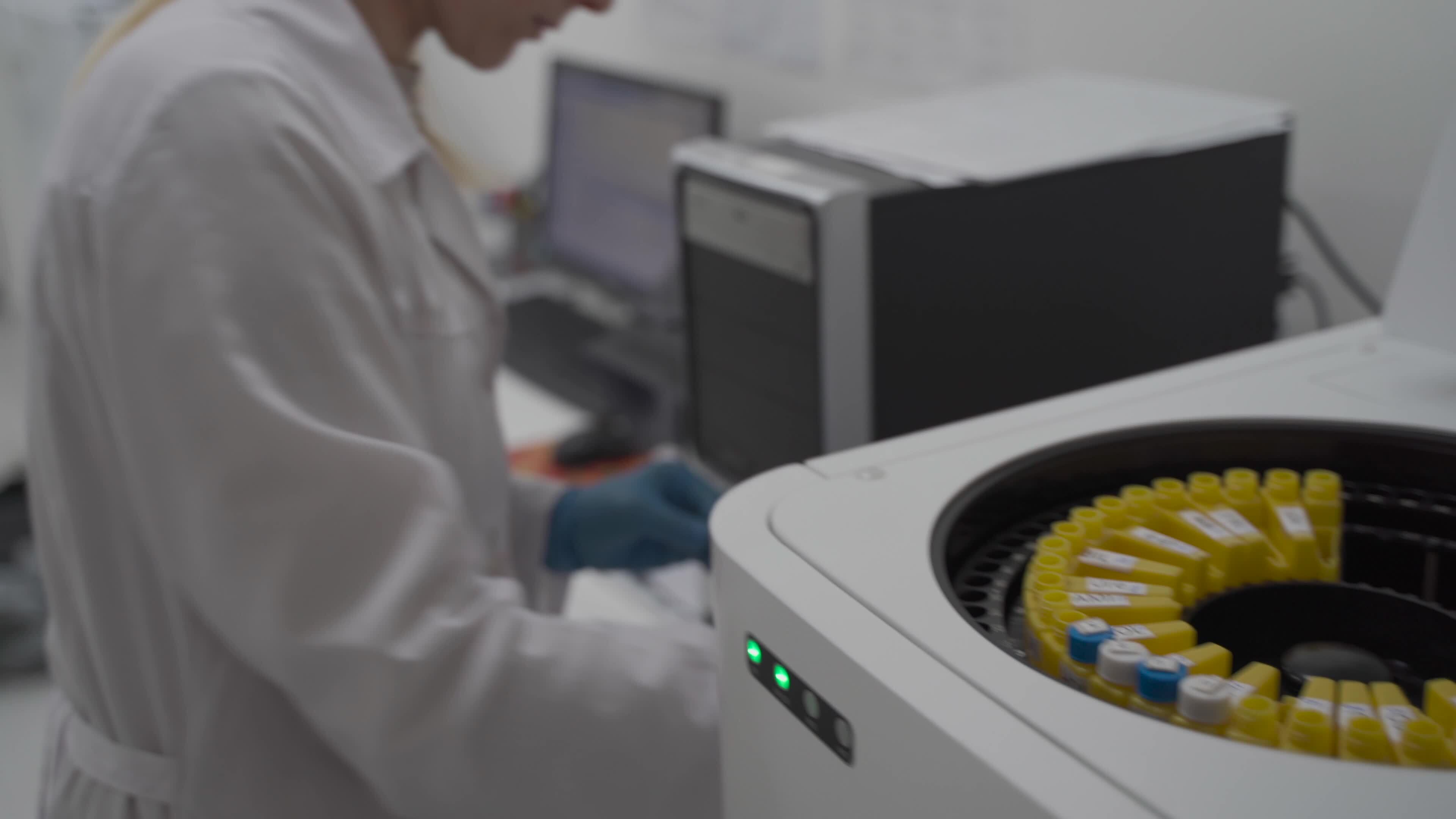 Lab technician in uniform places blood samples into automated robotic ...