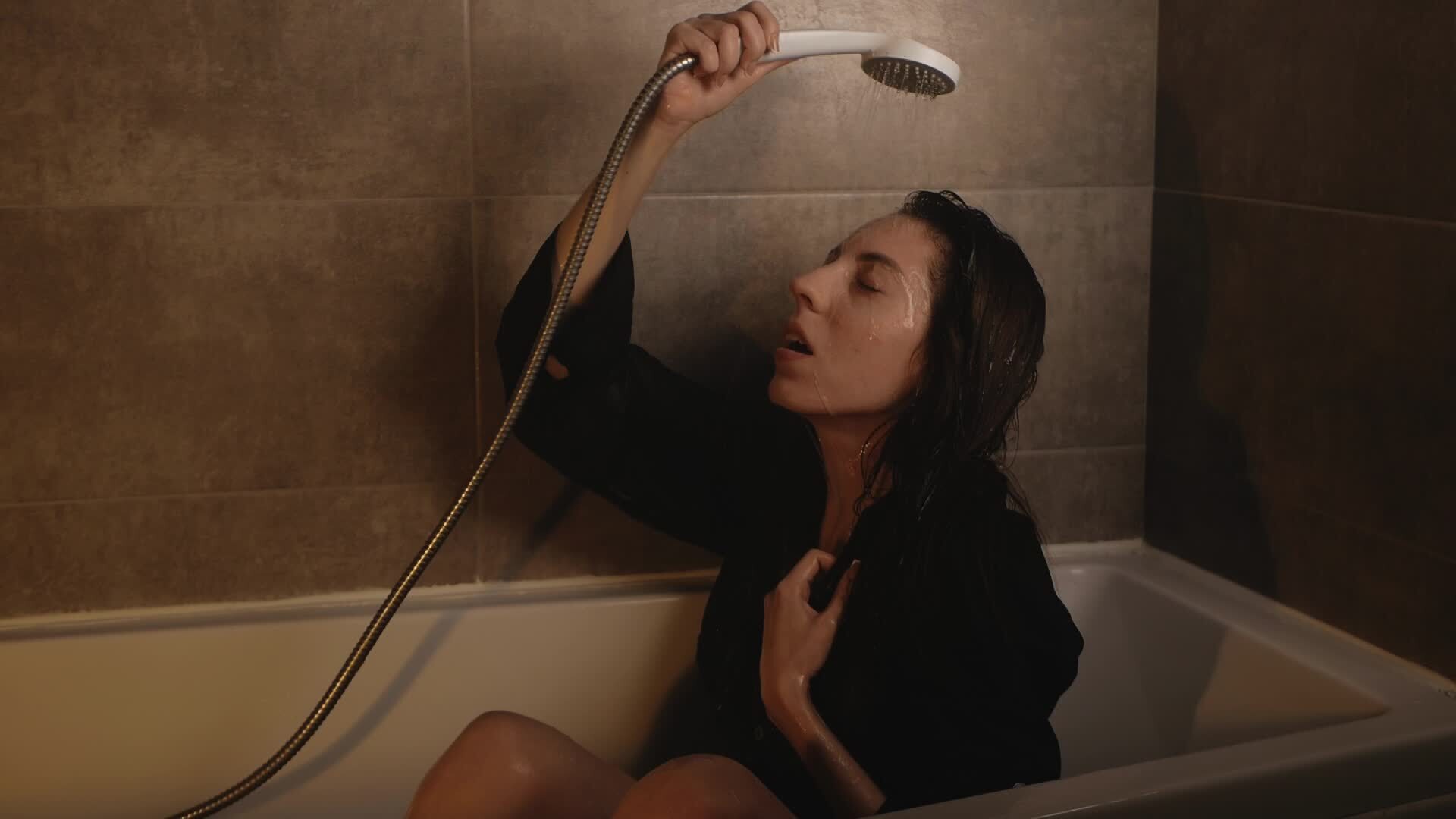 Woman pouring water on herself from shower while sitting in clothes 49536037 Stock Video at Vecteezy