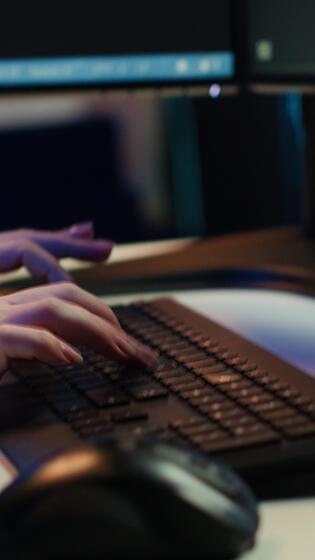 Vertical Programmer typing on computer to fix vulnerabilities in software enabling attackers to ...