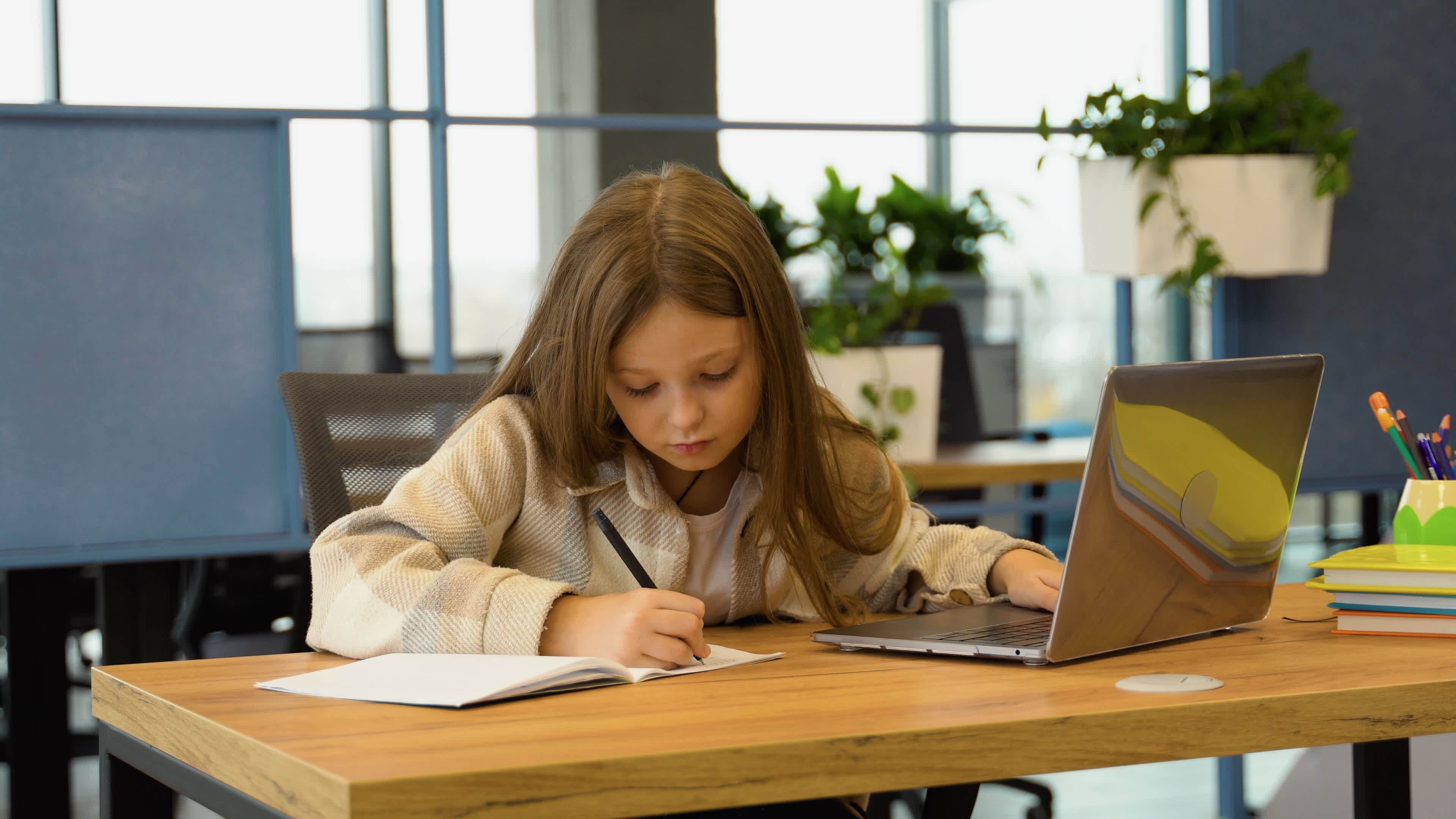 Pupil girl doing her homework using laptop in primary school. Child ...