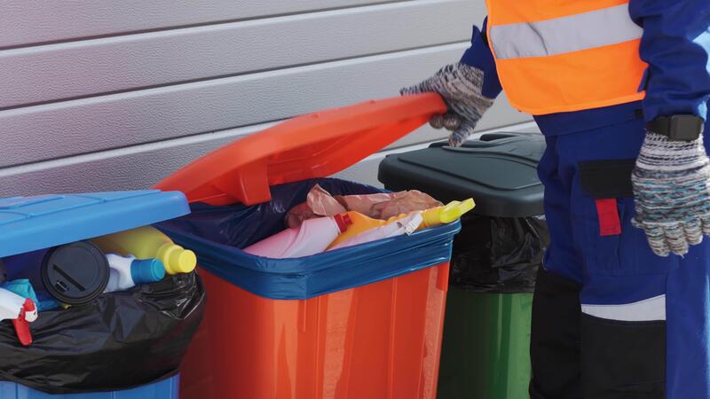 Waste management worker sorting recyclables in colorful bins at a ... Waste management worker sorting recyclables in colorful bins at a ...