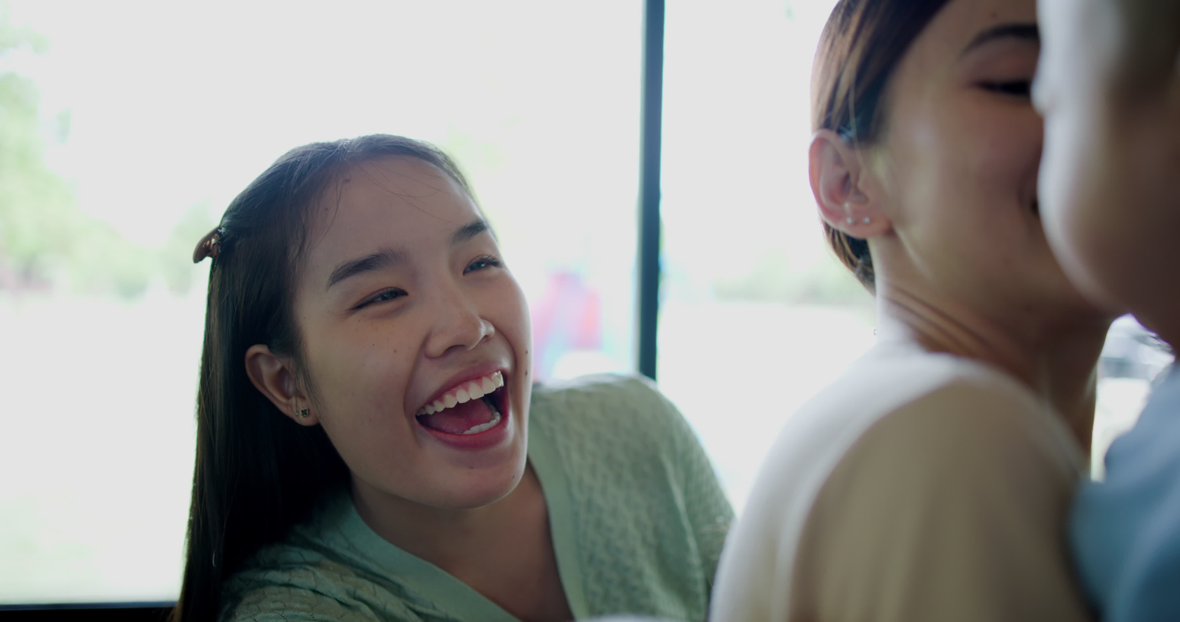 Handheld selective focus shot, Two happy women having fun playing with a little boy in a coffee ...
