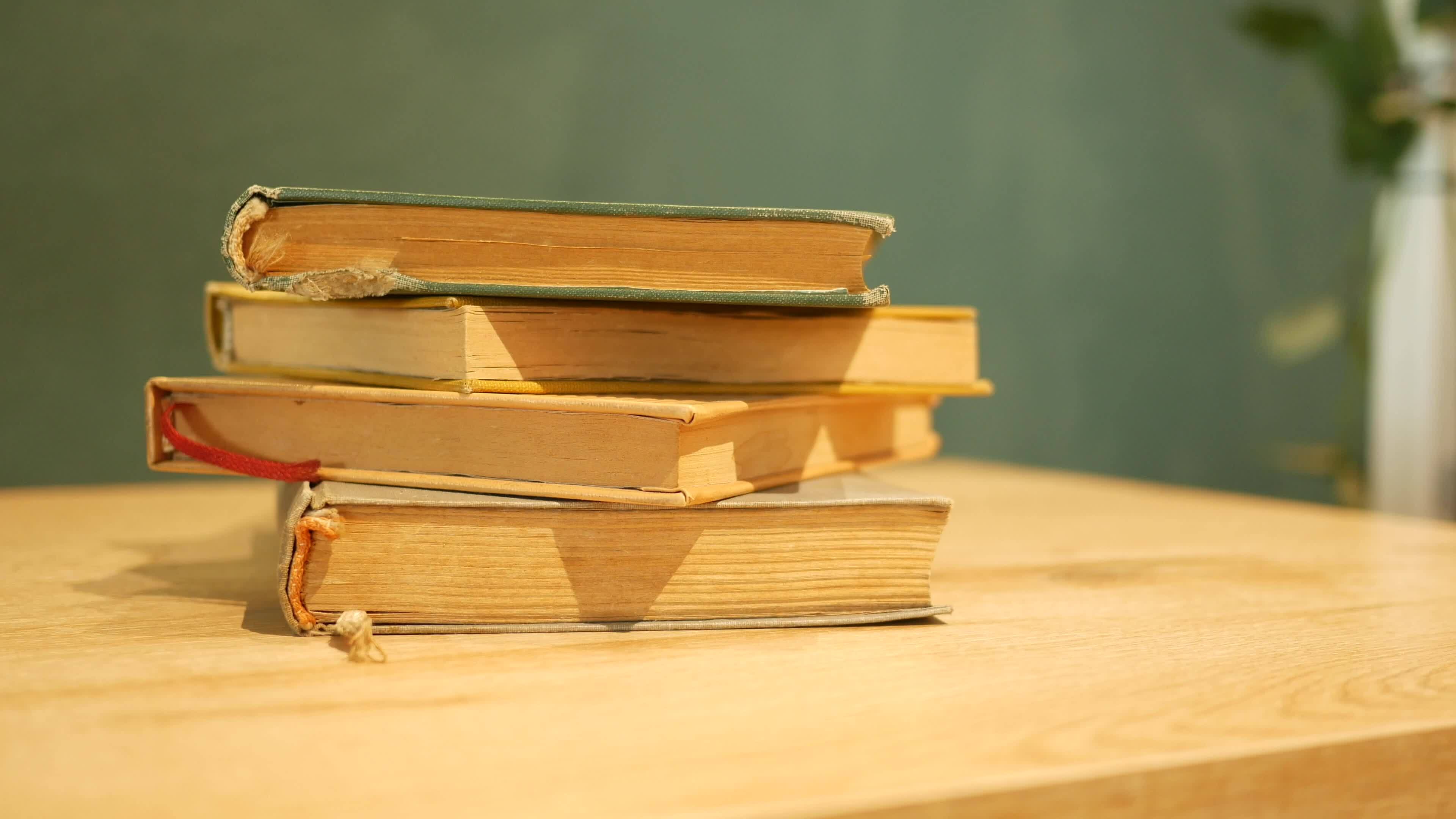 An open book with its pages gently turning rests on a wooden table in ...
