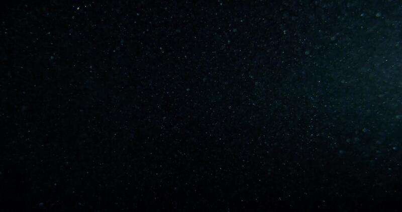 Cinematic dust particles floating on Black Screen Overlay. RED camera footage in slow motion ...