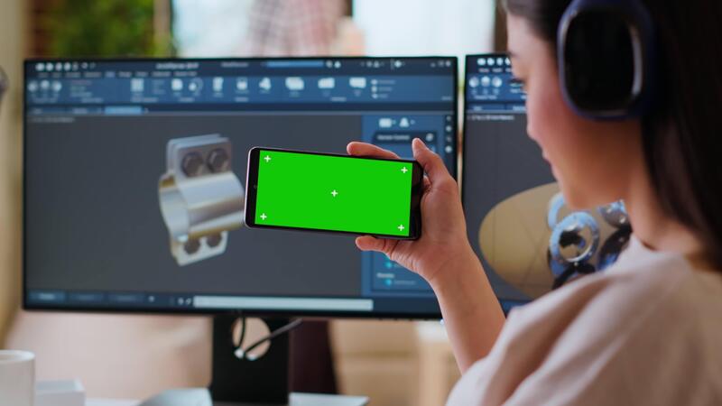 Software developer works in a modern office with green screen and dual ...