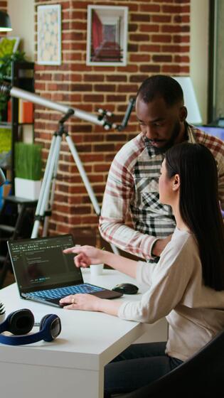 Vertical Interracial creative team programing code on a laptop and debugging, using digital ...
