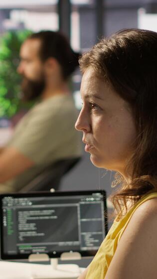 Vertical System administrator at work doing debugging of AI software using PC, checking glitches ...