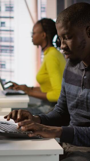 Vertical Programmer doing software debugging, asking for help from smiling team leader in ...