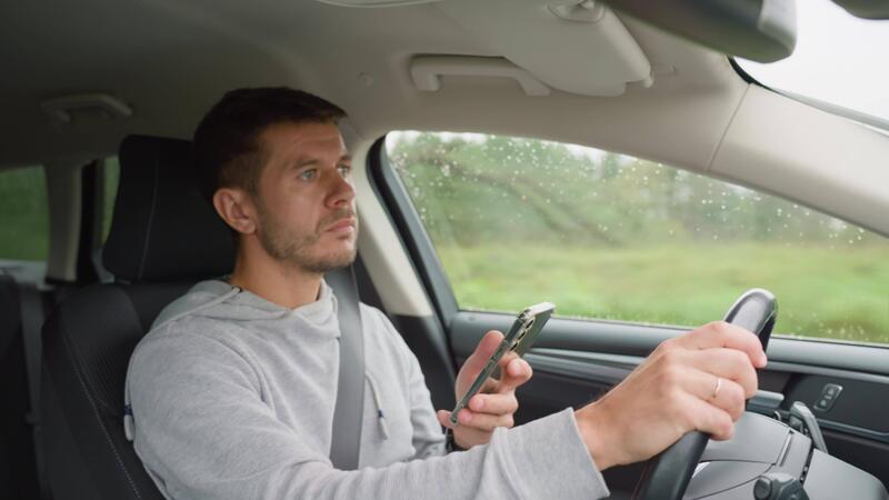 Driver using smartphone while driving car, distracted by messages on ...