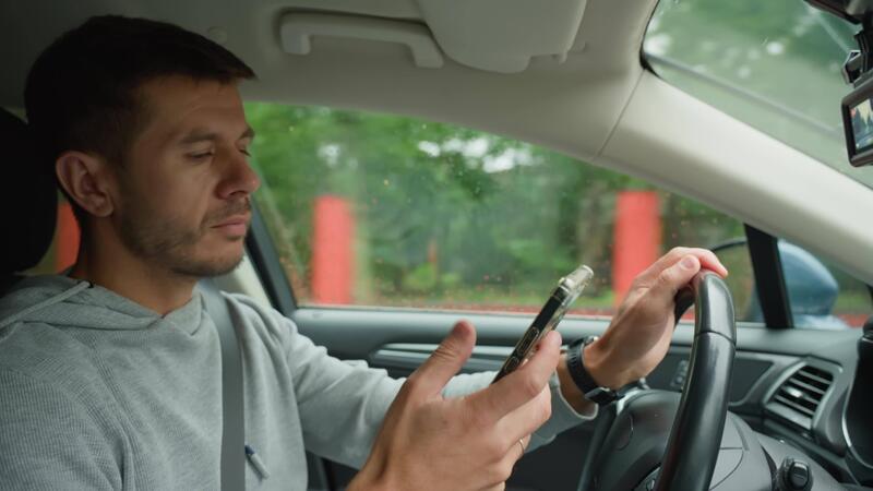Driver using smartphone while driving car, distracted by messages on ...
