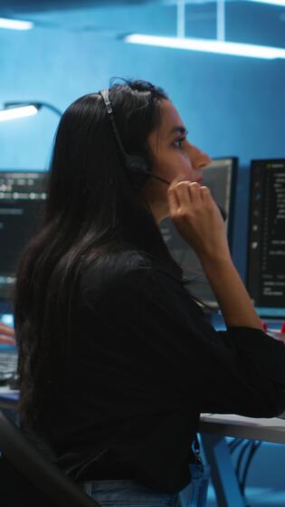 Vertical Woman Talking In Headphone Mic Doing System Analysis Of Server Farm Supercomputers It