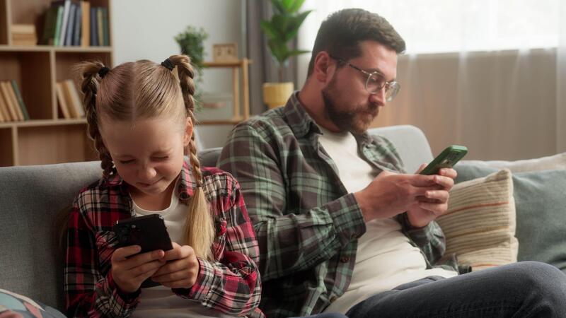 Gadget addiction. Caucasian family child daughter parent man father using mobile phone ...