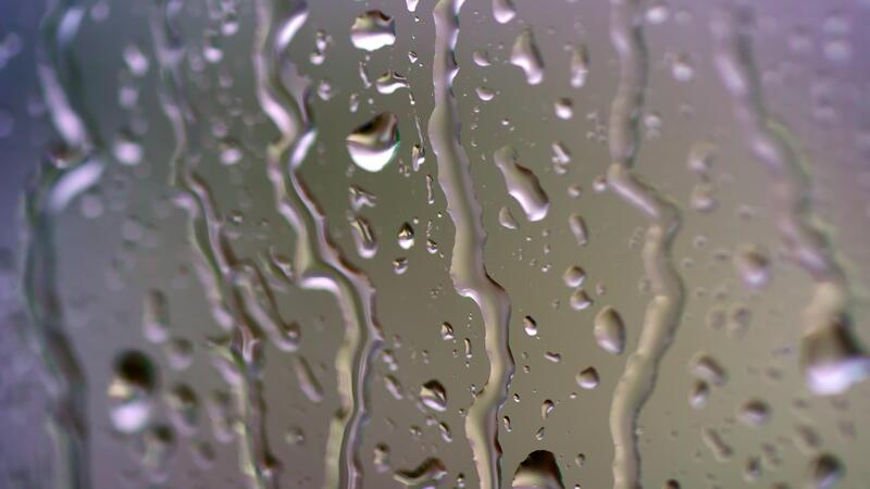 Water drops on glass. Large rain drops strike a window pane during a summer shower. Pure rain ...