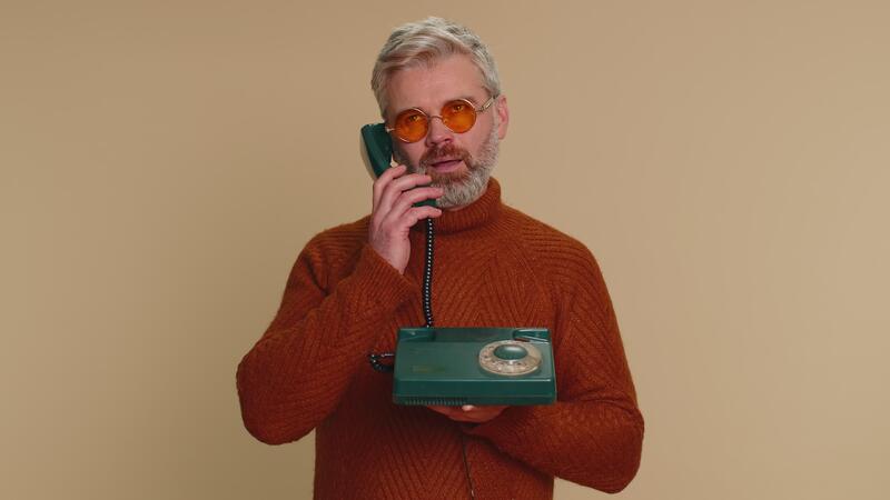Bored tired mature man talking on wired vintage old-fashioned telephone ...