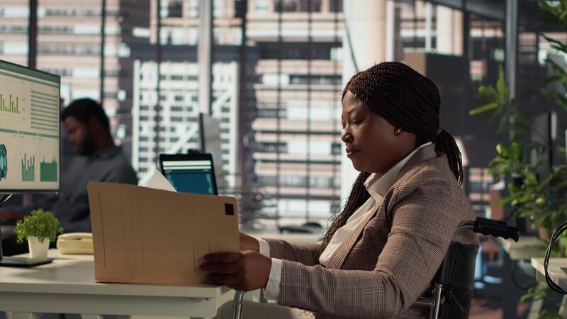 Female boss with chronic disability examining archived files and data ... Female boss with chronic disability examining archived files and data ...