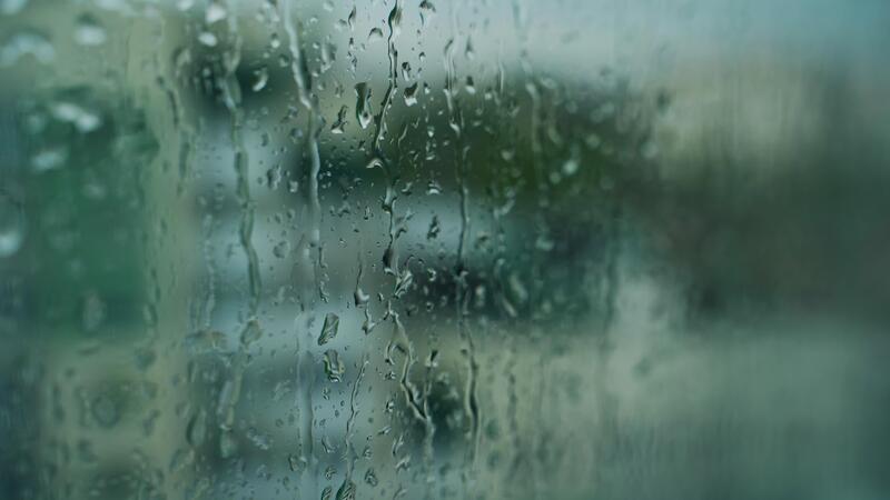 Falling drops on glass. Wet window on blur background. Rain drops running down the window ...