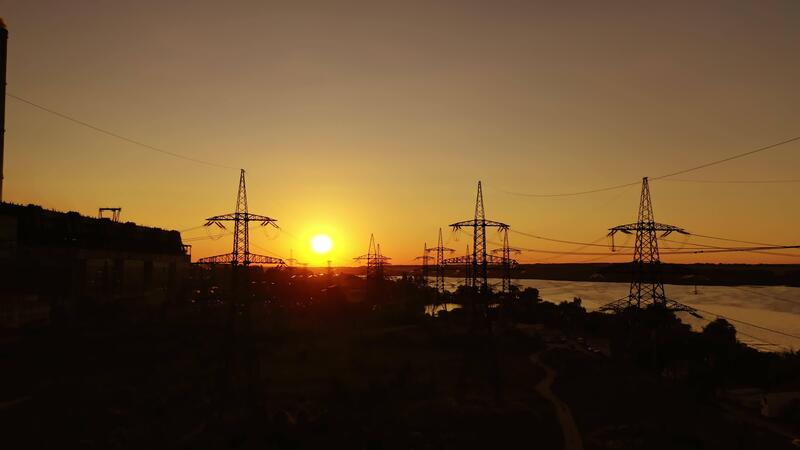 High voltage station at sunset. Tall pylons for electricity transmission. Silhouette of electric ...