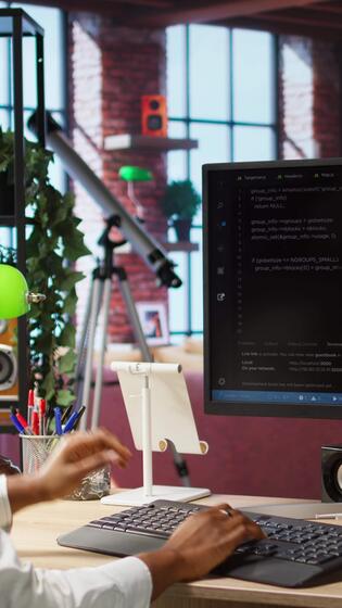 Vertical Software developer wearing headphones using computer at home for artificial ...