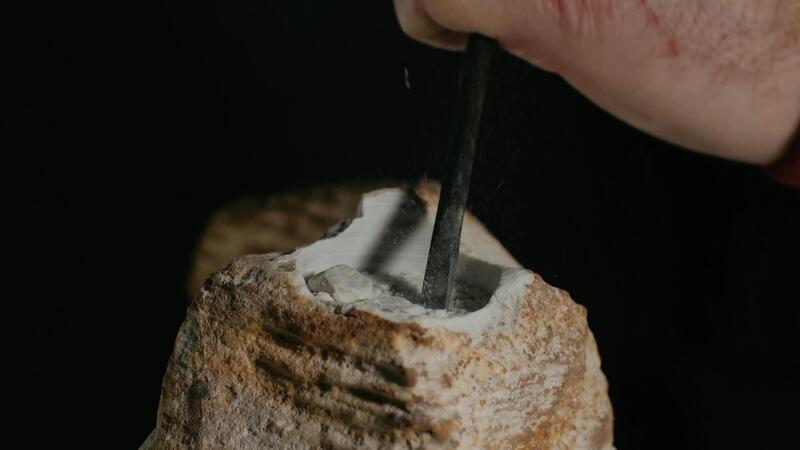 Close-up of a chisel being used to chisel a stone to create a sculpture ...