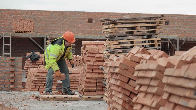 Construction worker organizing brick stacks at a building site, Worker ...