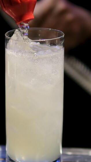 pour soda into a glass Bartender ice cubes making cocktail at bar. Various glasses for alcoholic ...