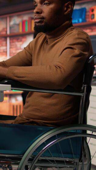 Vertical Man in wheelchair working in inclusive AI tech agency providing software development ...