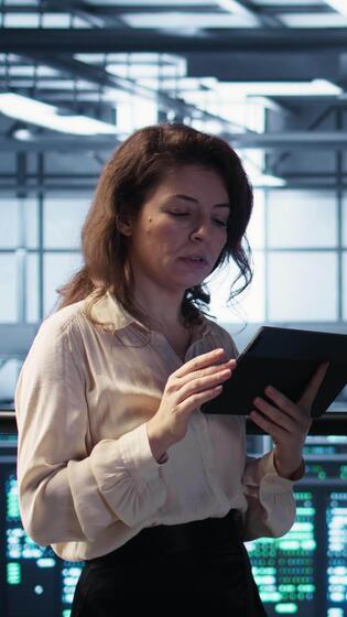 Vertical Smiling admins using laptop in data center, managing server virtualization. Cheerful IT ...