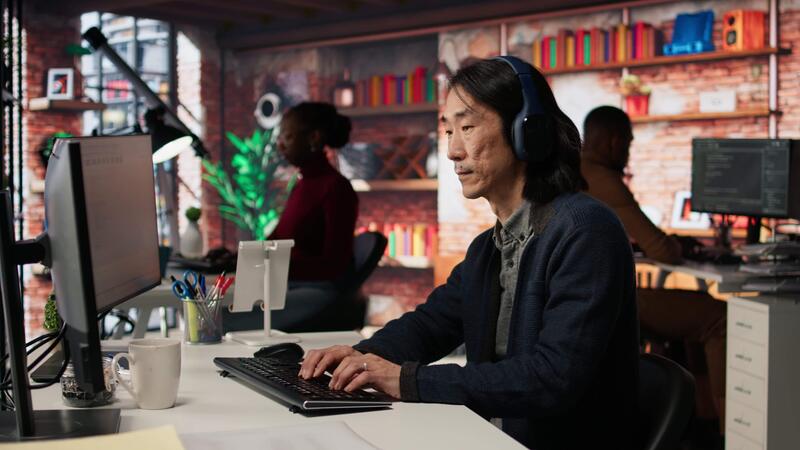 AI startup office chief technology officer listening music while coding application. Senior ...