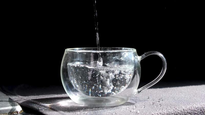 Pure Water Poured Into Glass closeup on light gray background. Quenching thirst concept. Clear ...