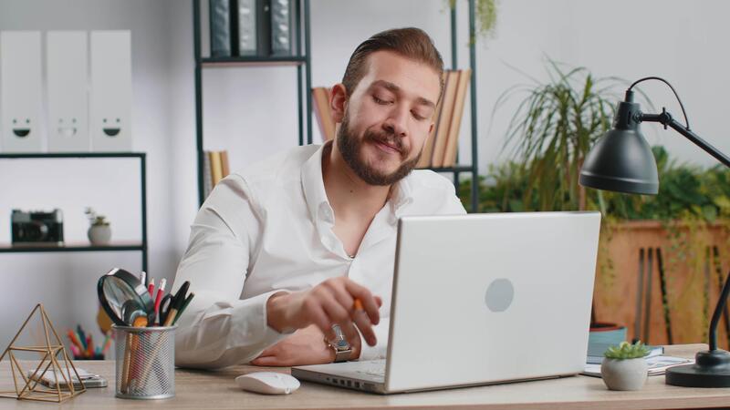 Lebanese business man sitting at office workplace desk closing laptop pc after finishing remote ...