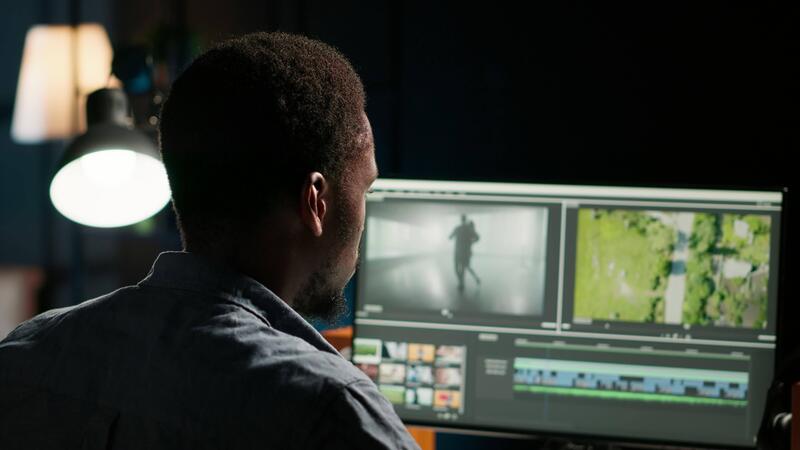 Black guy editor working with dual monitors for creative content, editing footage and does color ...