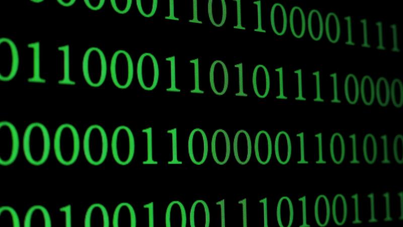 A close-up of glowing green binary code , ones and zeros on a black digital screen, symbolizing ...