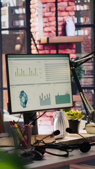 Vertical Computer monitors on office desk showing data analytics dashboards and performance ...