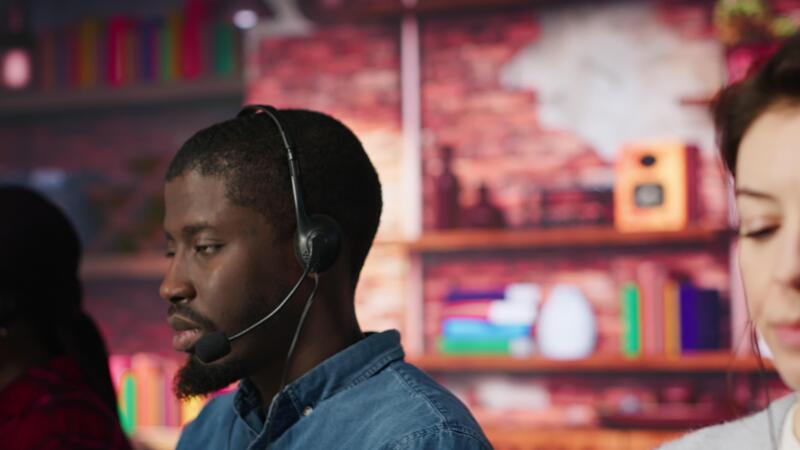 Call center employees wearing headset assisting customers in office. Workers doing customer ...