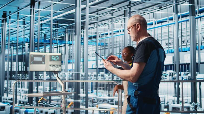 Senior engineer in smart photovoltaics factory looking at system performance metrics on tablet ...