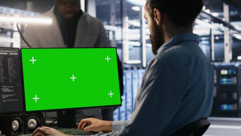 Close up of server farm system administrator using green screen PC to monitor neural network AI ...